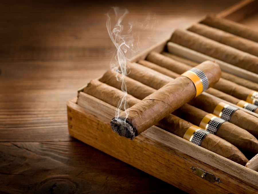 smoking cuban cigar over box on wood background | Whiskypedia